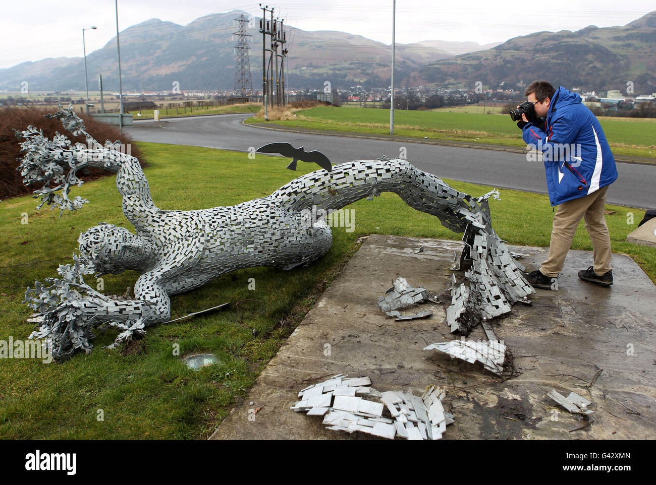 A man takes a picture of a giant sculpture created by artist Andy Scott ...