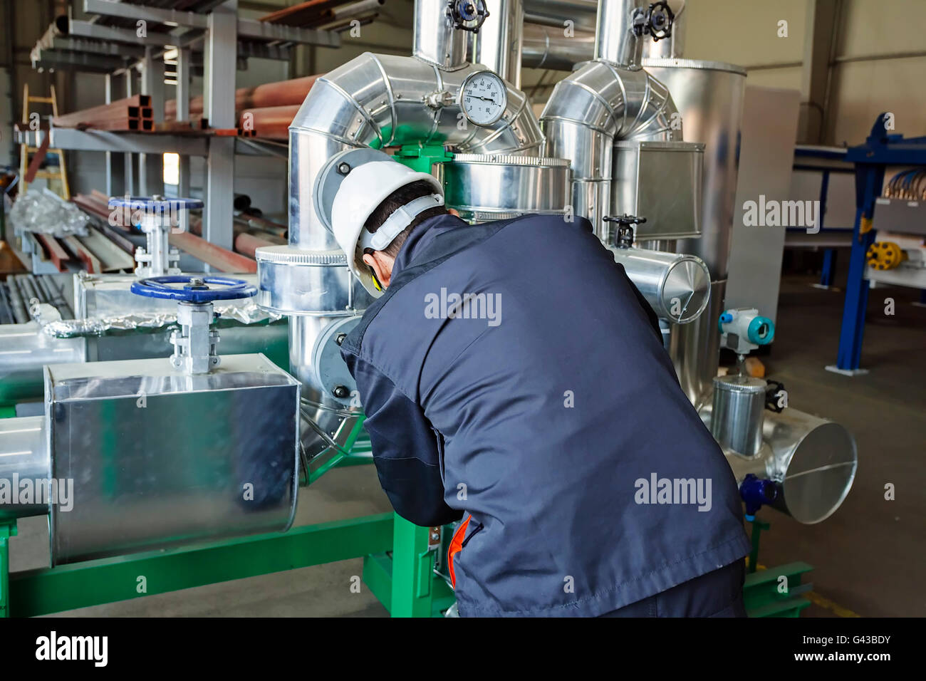Man worker checking advanced industrial engine in the production hall ...