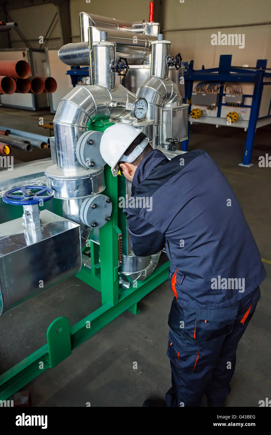 Man worker checking advanced industrial engine in the production hall ...