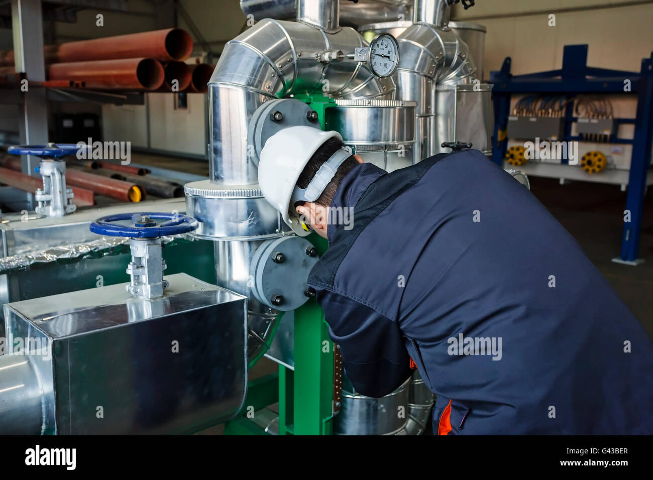 Man worker checking advanced industrial engine in the production hall ...