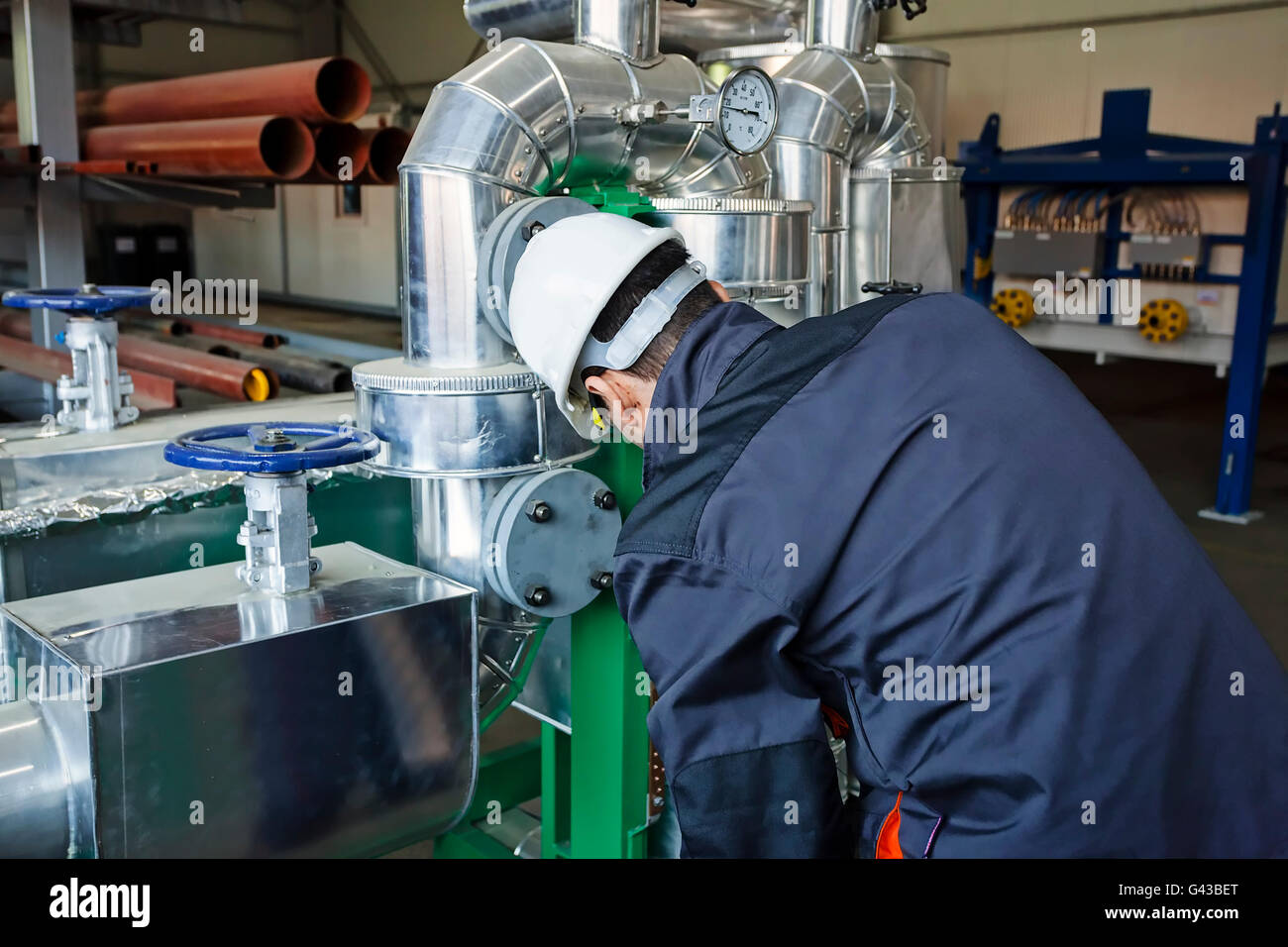 Man worker checking advanced industrial engine in the production hall ...