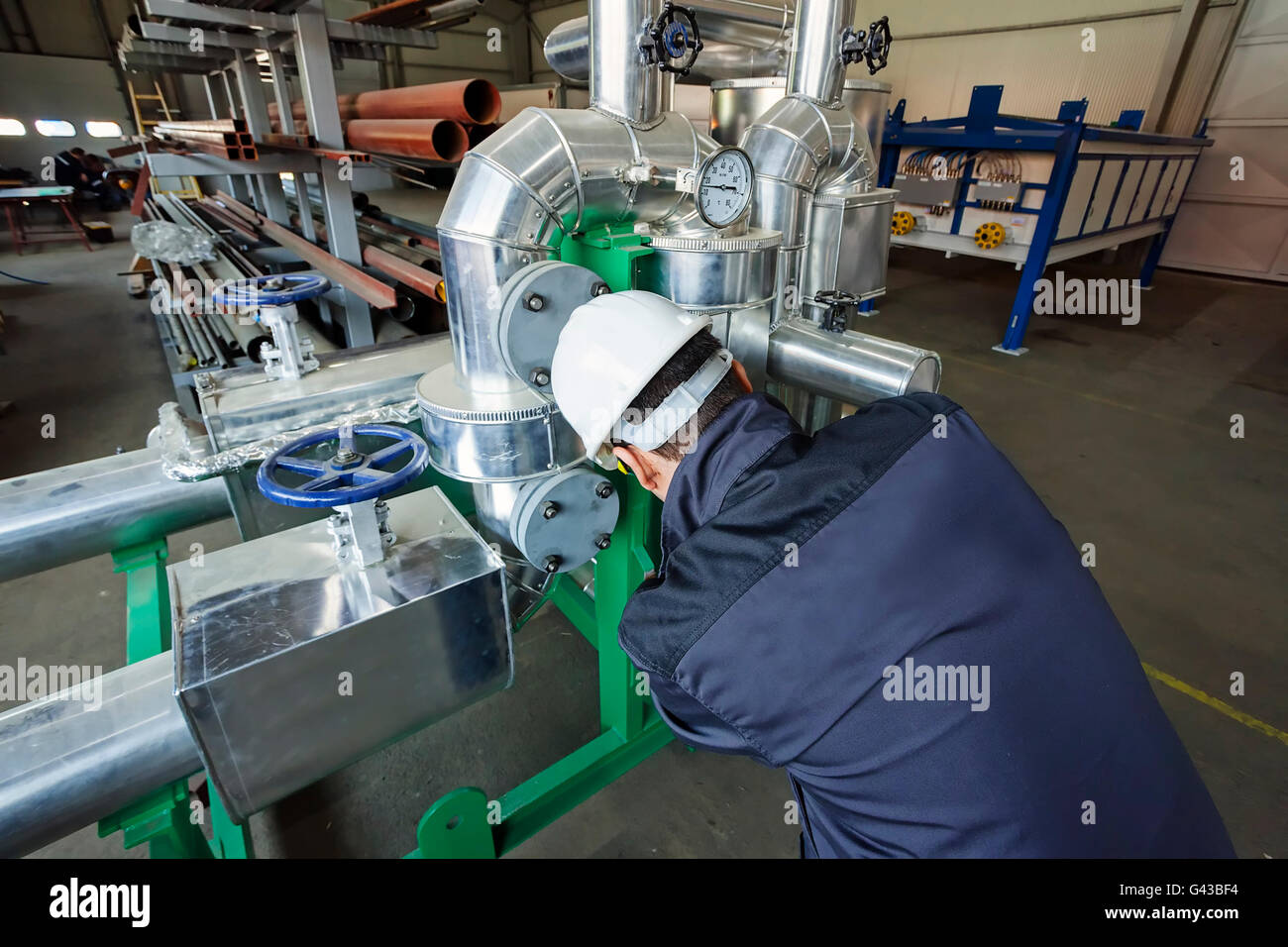 Man worker checking advanced industrial engine in the production hall ...