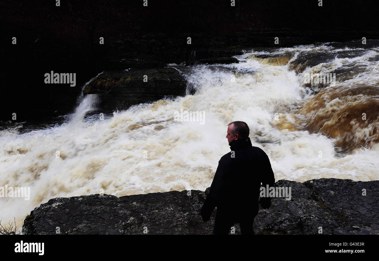 A man stands to watch the River Ure, as it is swelled by the rain water ...