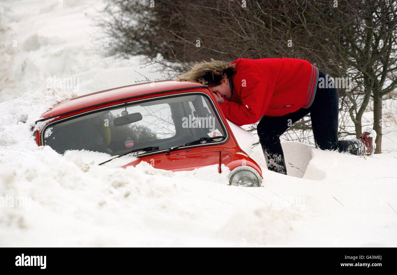 A stranded woman driver checks on the condition of her Mini trapped in ...