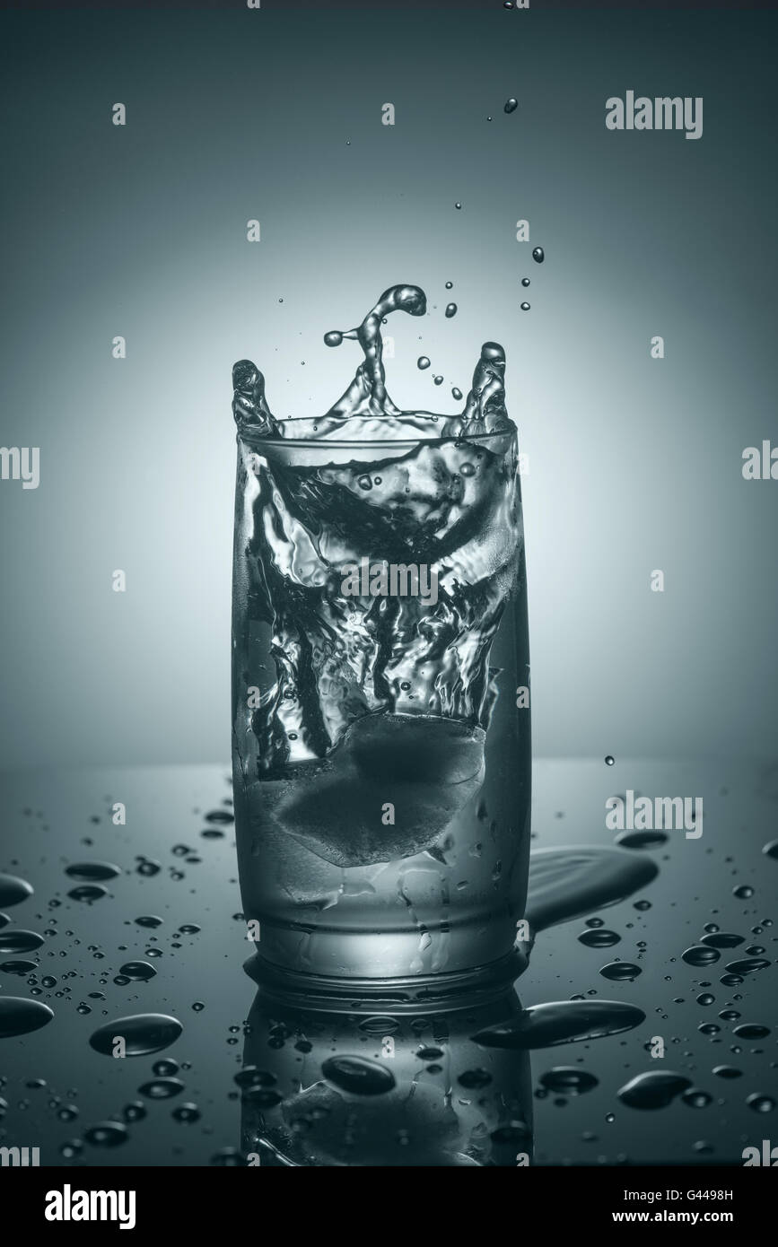 Splashes in a glass of pure cold water with an ice cube Stock Photo - Alamy