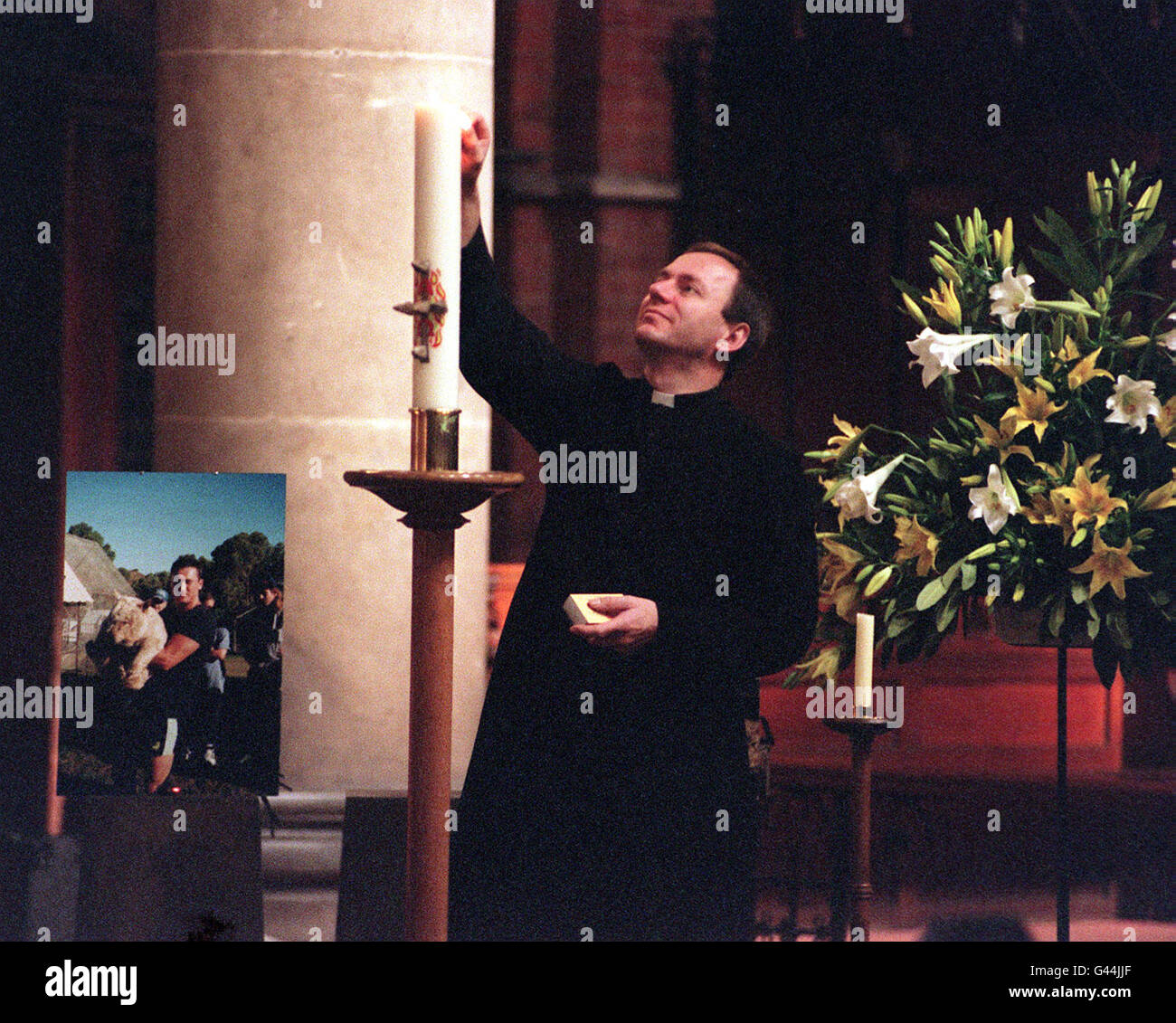 Father Colin Copper lights a candle near a photograph of murdered ...