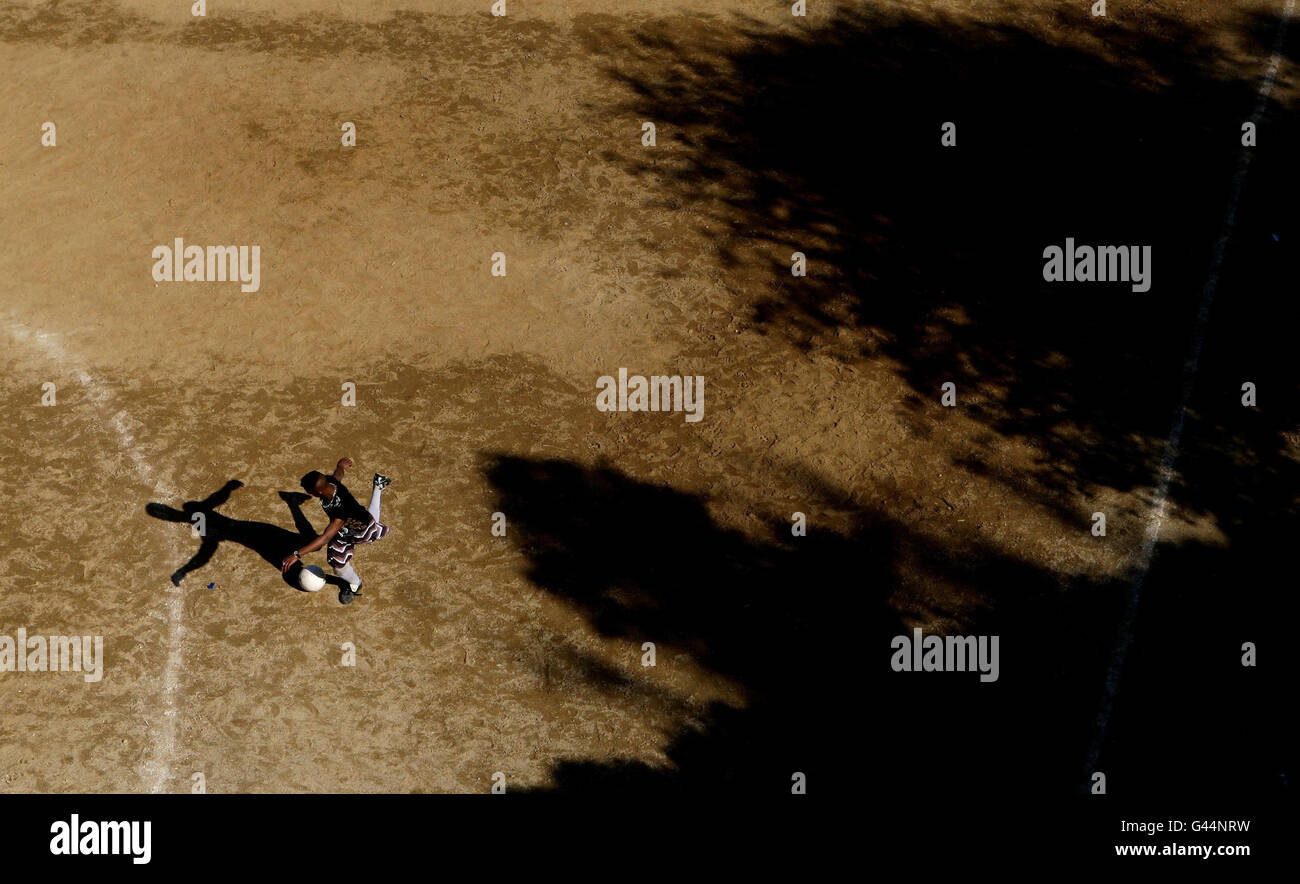 A young boy plays football alone on a dusty pitch in Barcelona, Spain ...