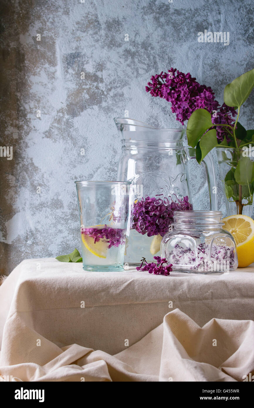 Glass jar of lilac flowers in sugar, glass and pitcher of lilac water ...