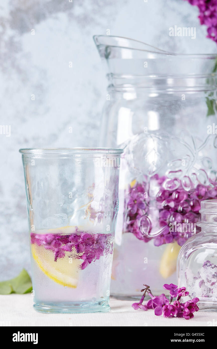 Glass jar of lilac flowers in sugar, glass and pitcher of lilac water ...