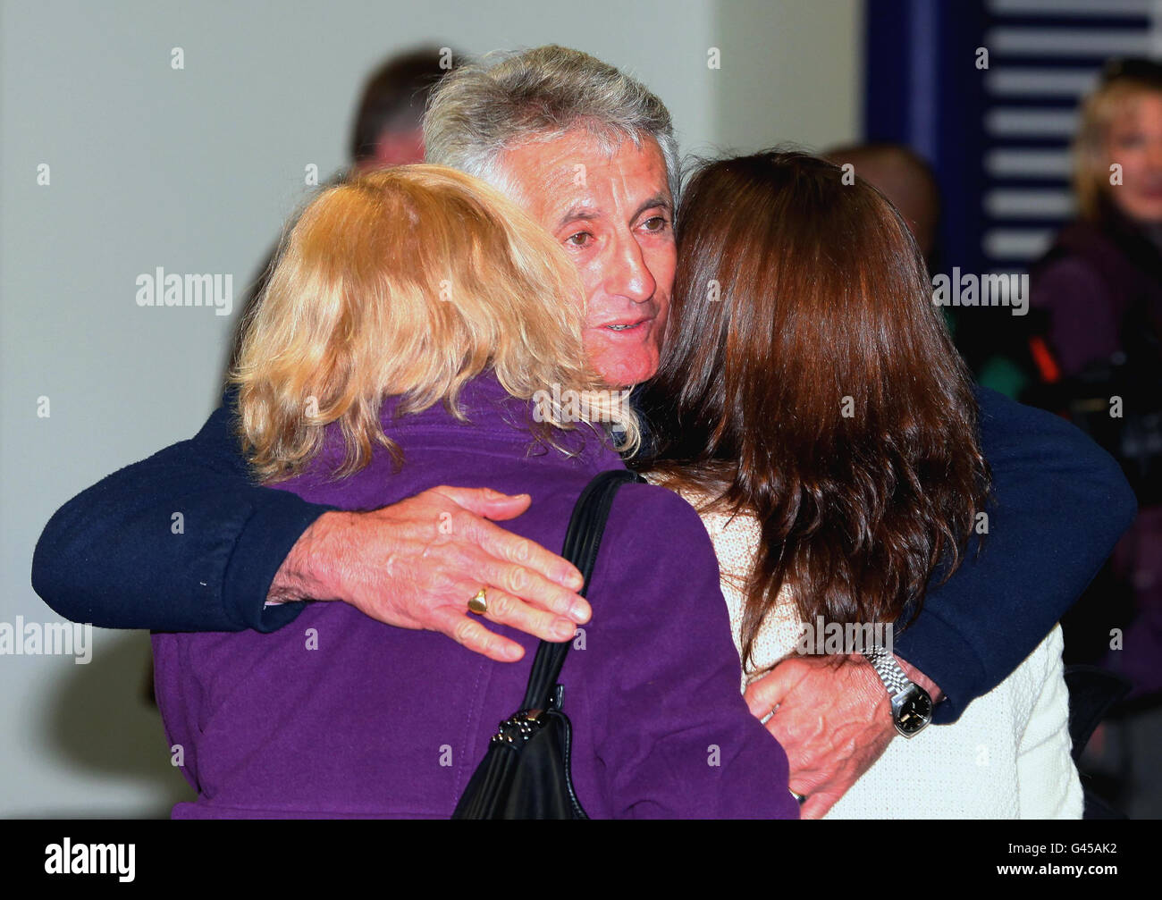A man (no name given) receives a hug from family members on arriving at ...