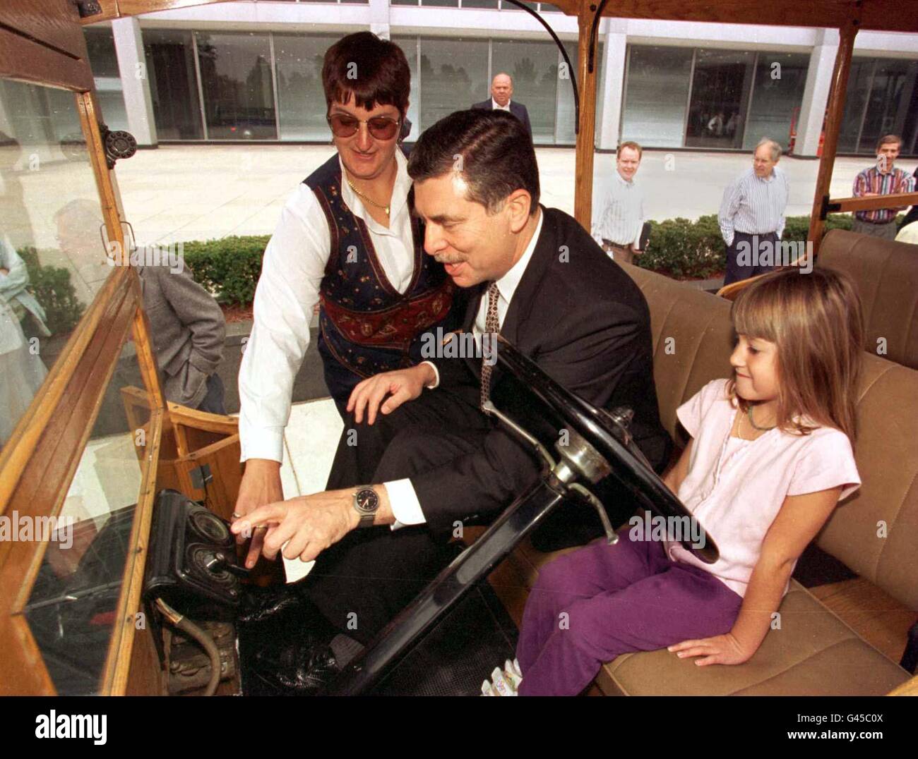 Ford Motor Company Chairman Alex Trotman (center) gets a quick lesson ...