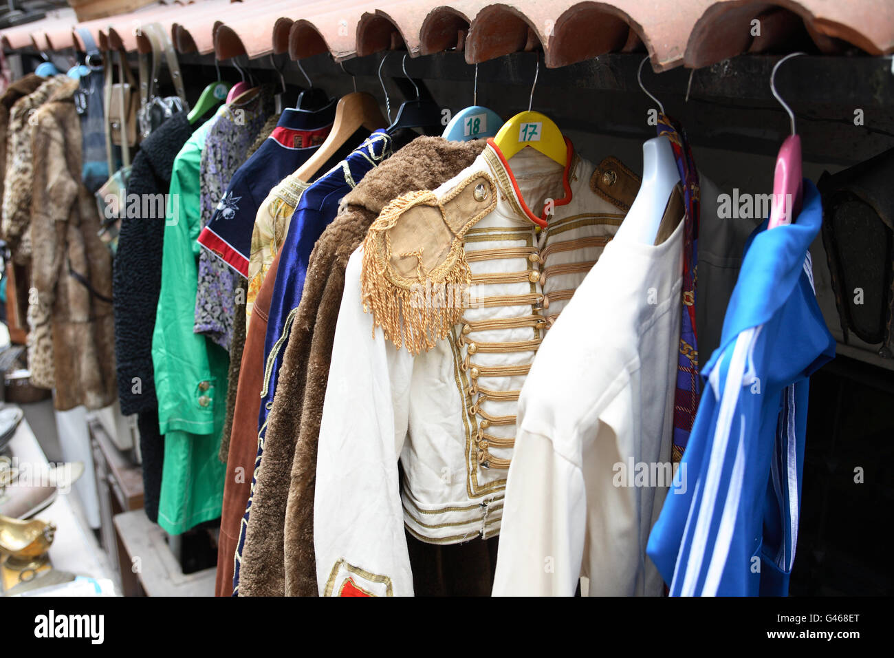 Curiosity shop. Various vintage clothing hanging on hangers outdoor ...