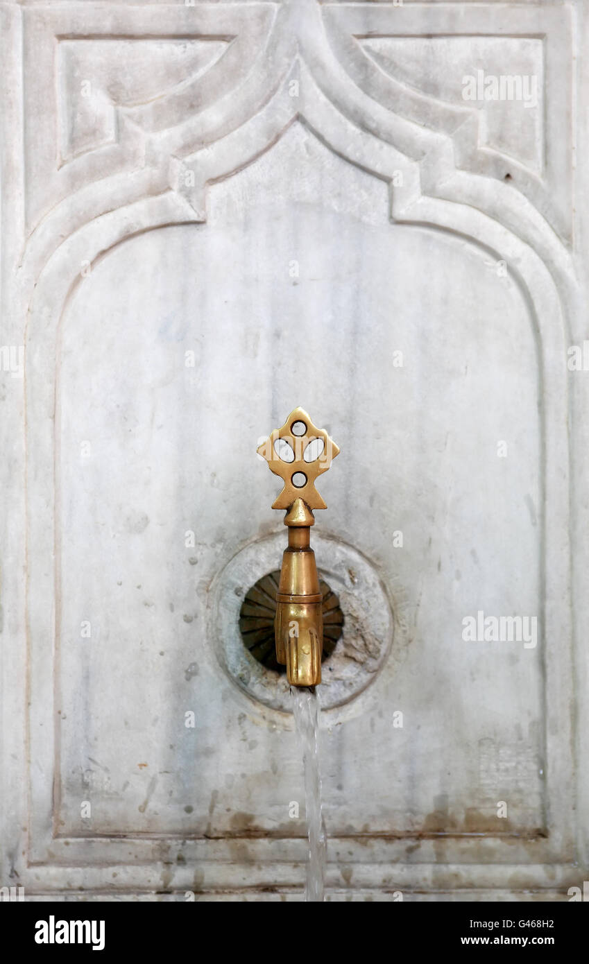 Ancient bronze faucet with flowing water for traditional islam ablution ...
