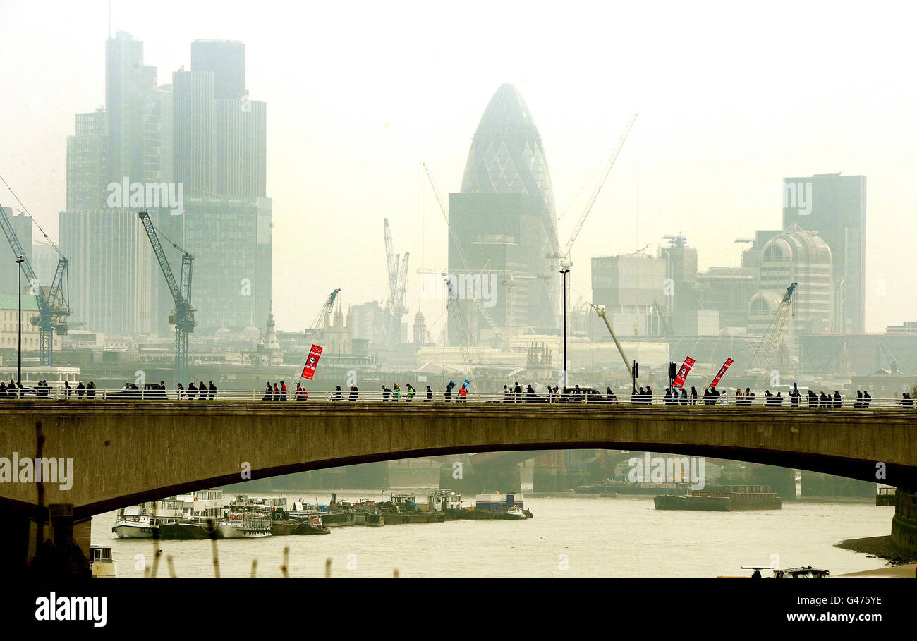 Demonstrators march across Waterloo Bridge, with the City of London in ...