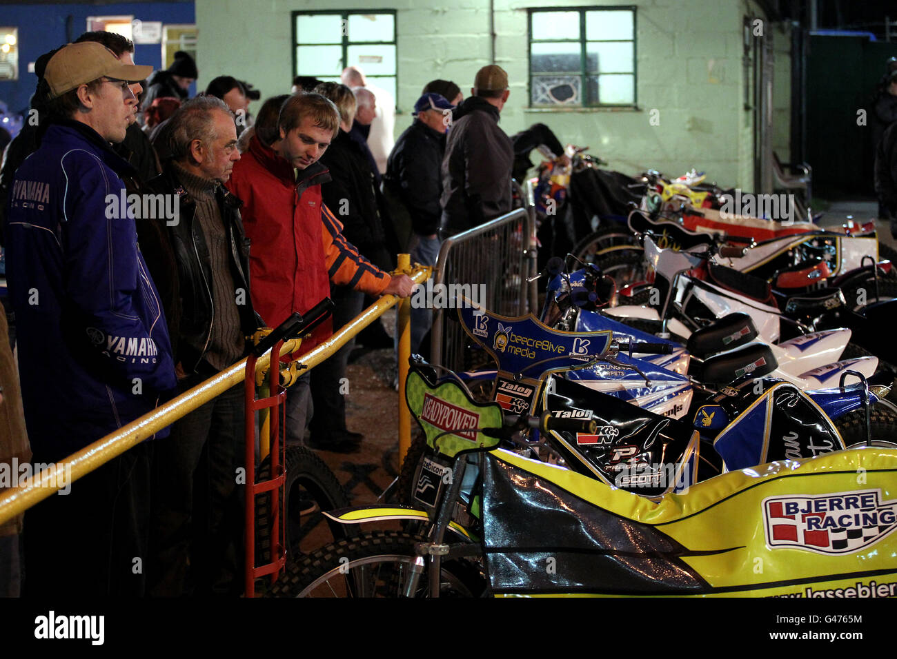 Spectators look on as Riders and Mechanics work on bikes in the pit ...
