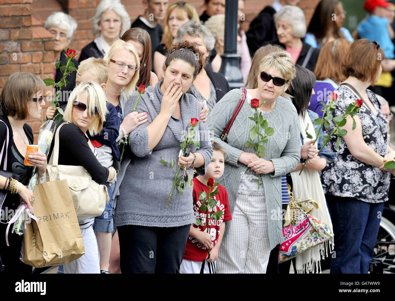 Mourners holds flowers as a hearse carrying the coffin of Sian O ...
