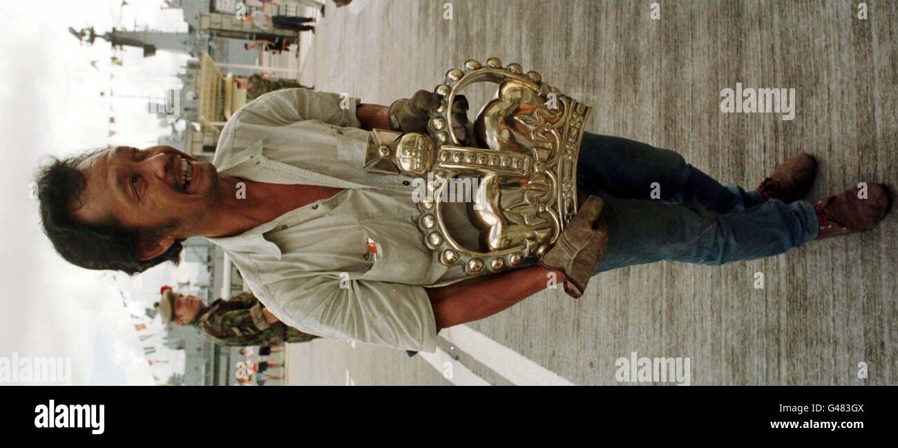 A local workman carries part the tri-service crest after cutting it ...