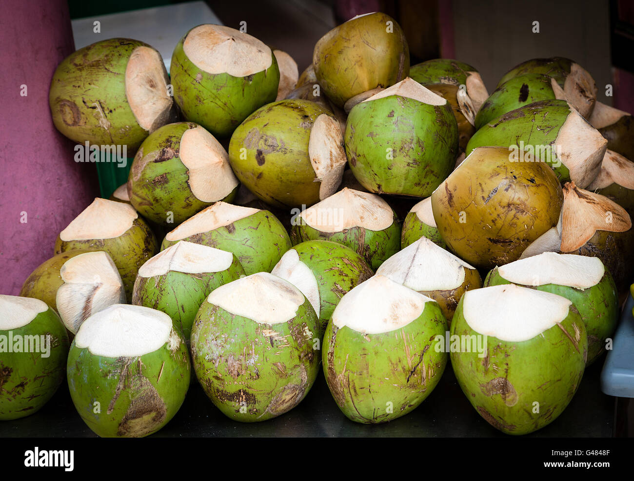 Bunch of coconuts with the top cut ready for sale at a street market ...