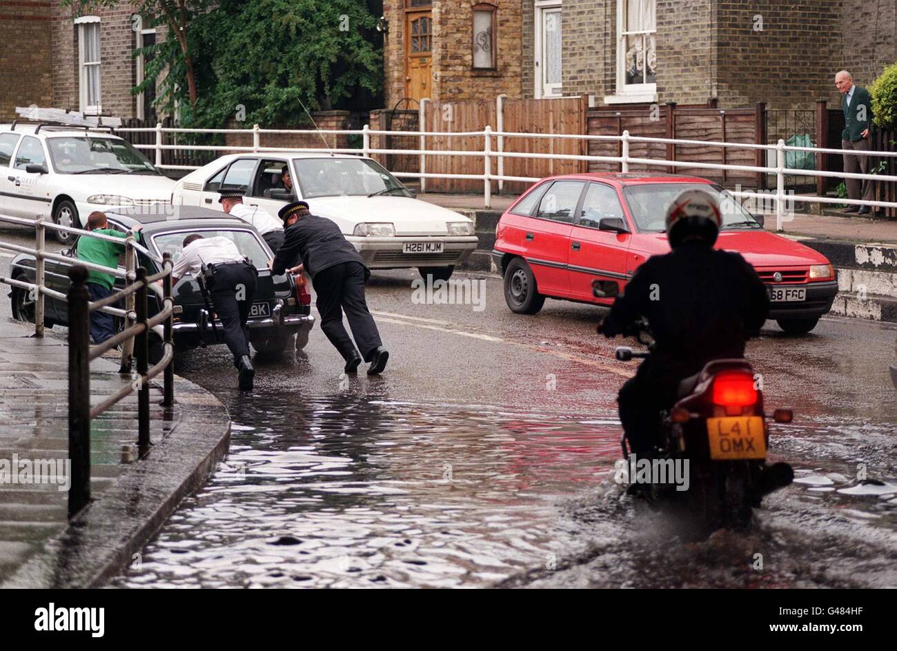 Police officers assist a motorist whose MGB GT stalled in flooding in ...