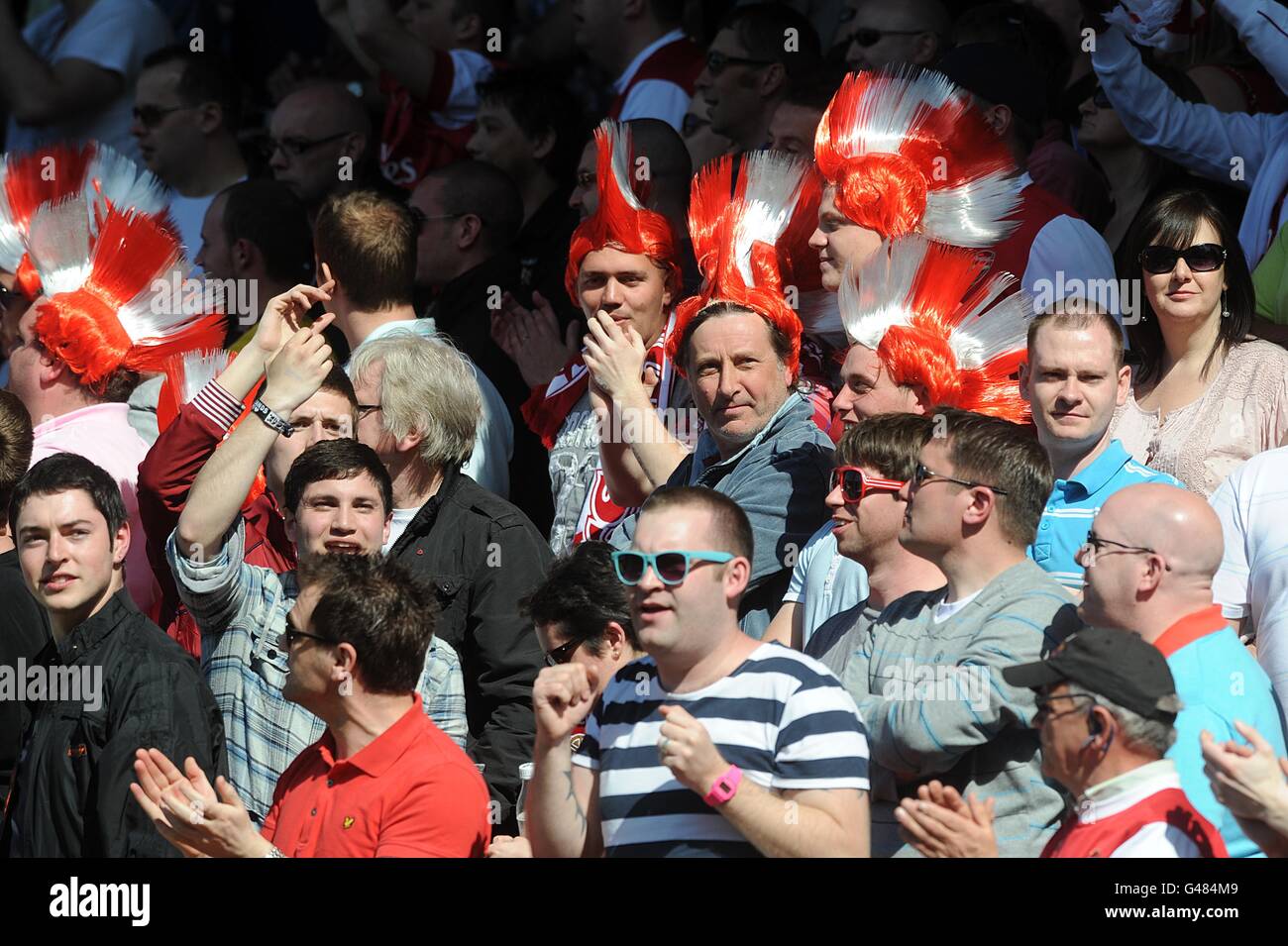 Fans wear colourful red and white mohawk wigs in the stands Stock Photo ...