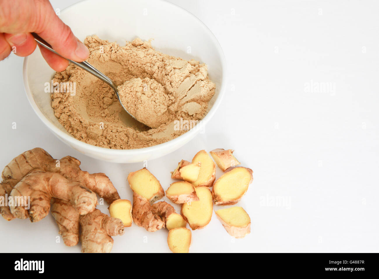 Ginger powder in bowl with metal spoon, hand holding metal spoon ...