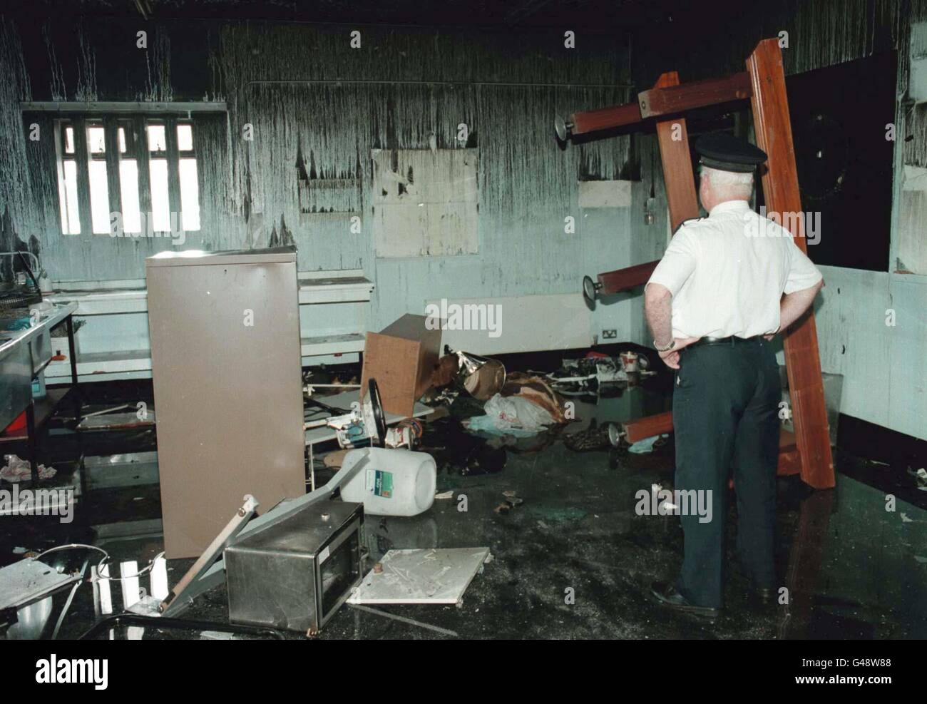 A prison officer stands in the wrecked remains of a cell in the ...