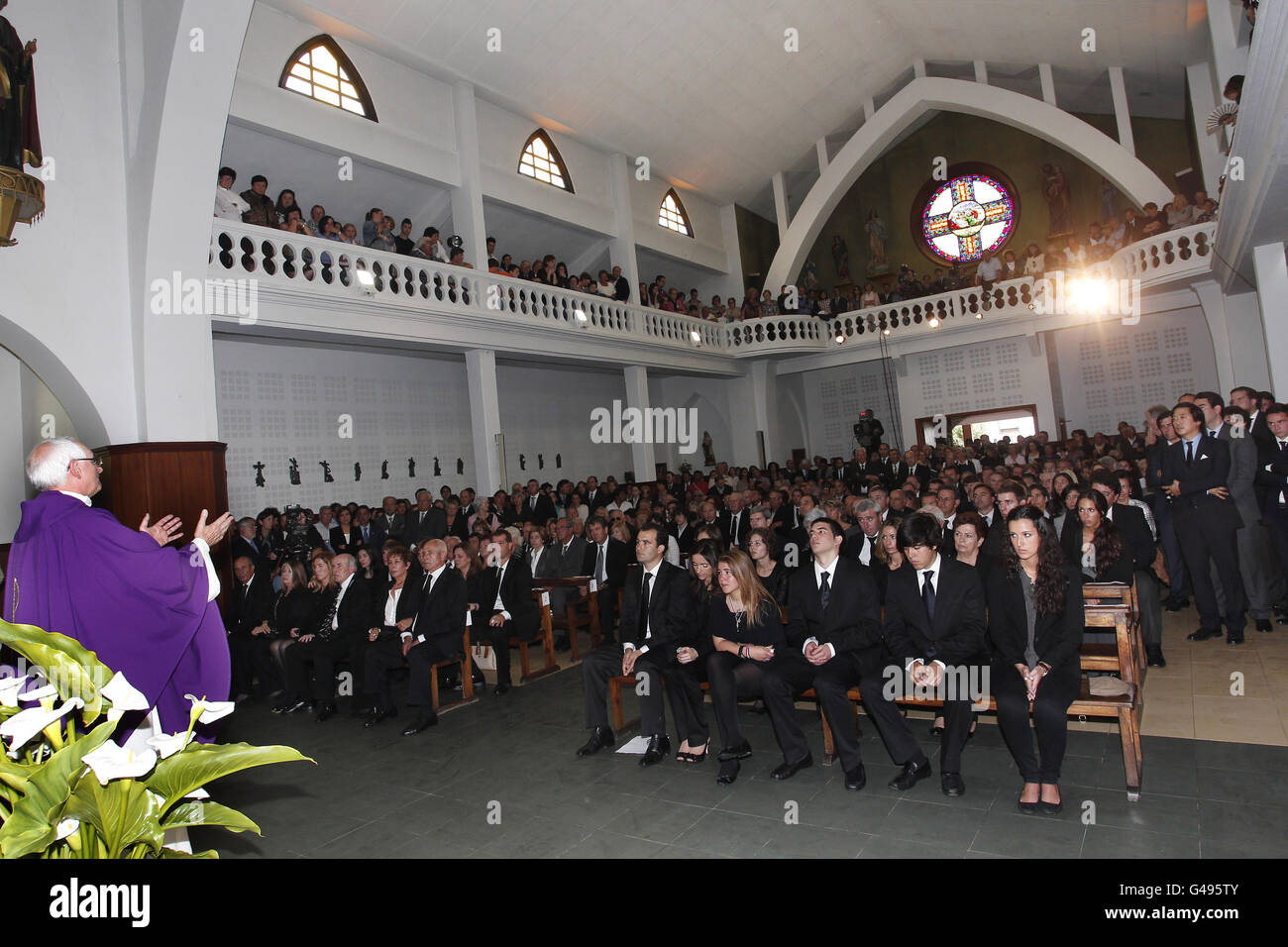 Priest Juan Cuevas (left) presides over the funeral service inside the ...
