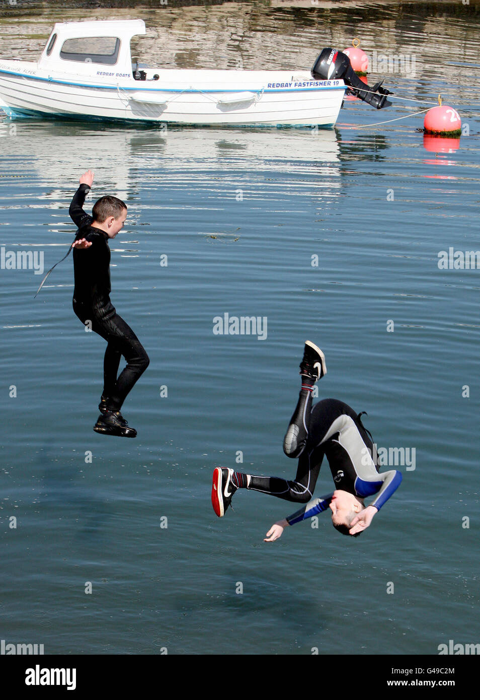 Youths jump into the sea at Carnlough Harbour in Co Antrim, as the warm ...