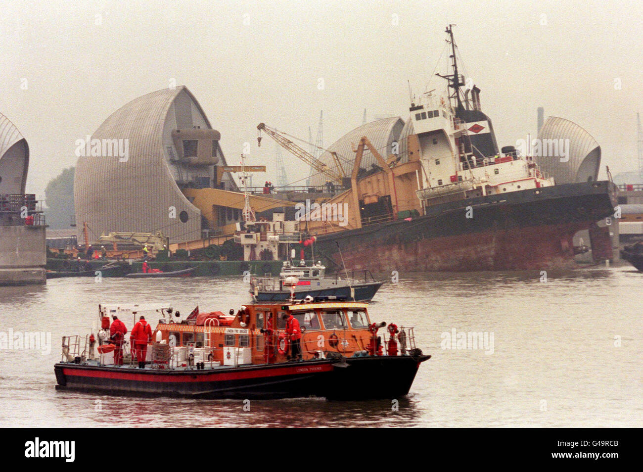 A 3,000-tonne ship (in background) sits half submerged in water after ...