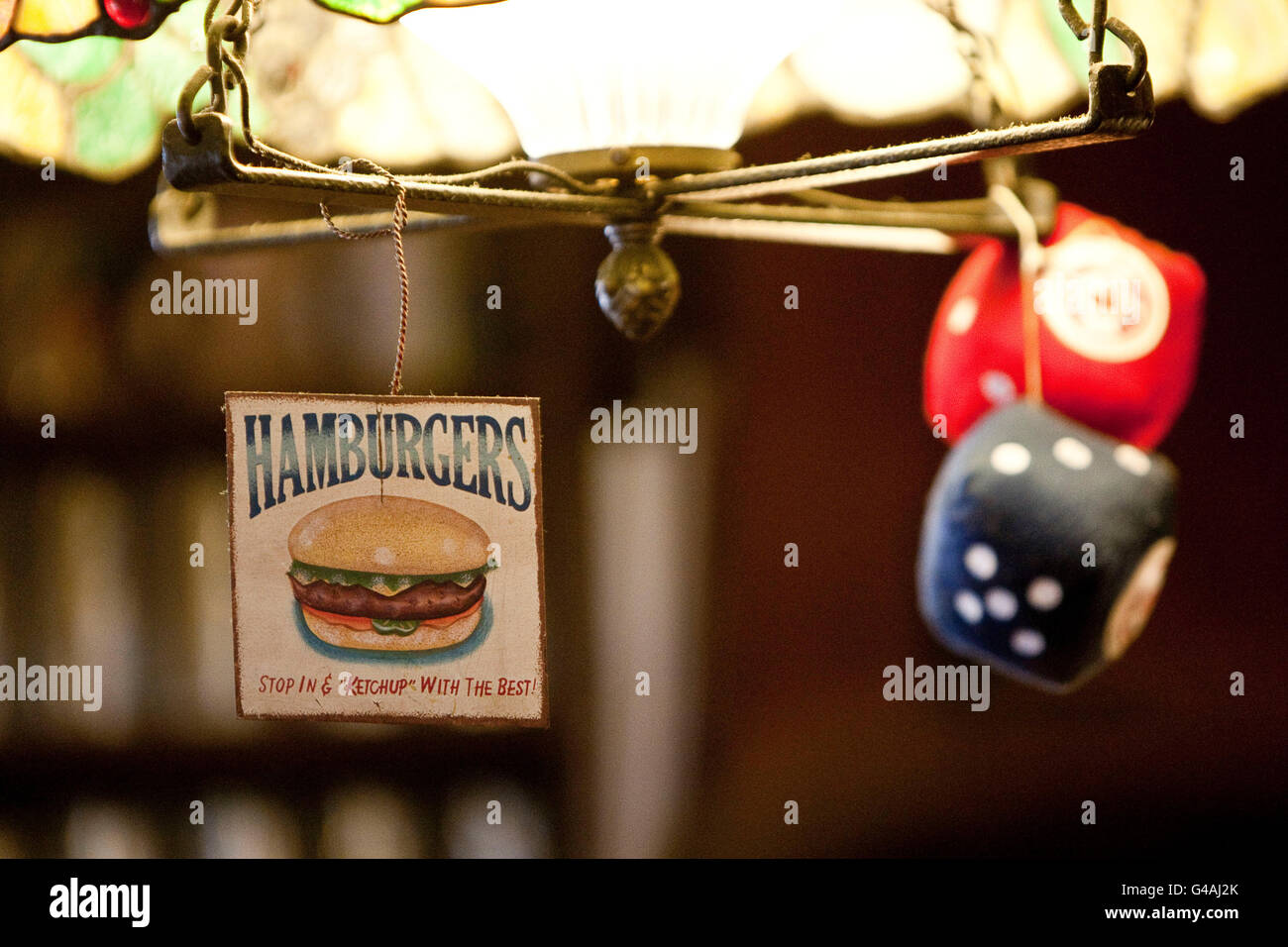 A "stop in and ketchup with the best" hamburger sign hangs of a light ...