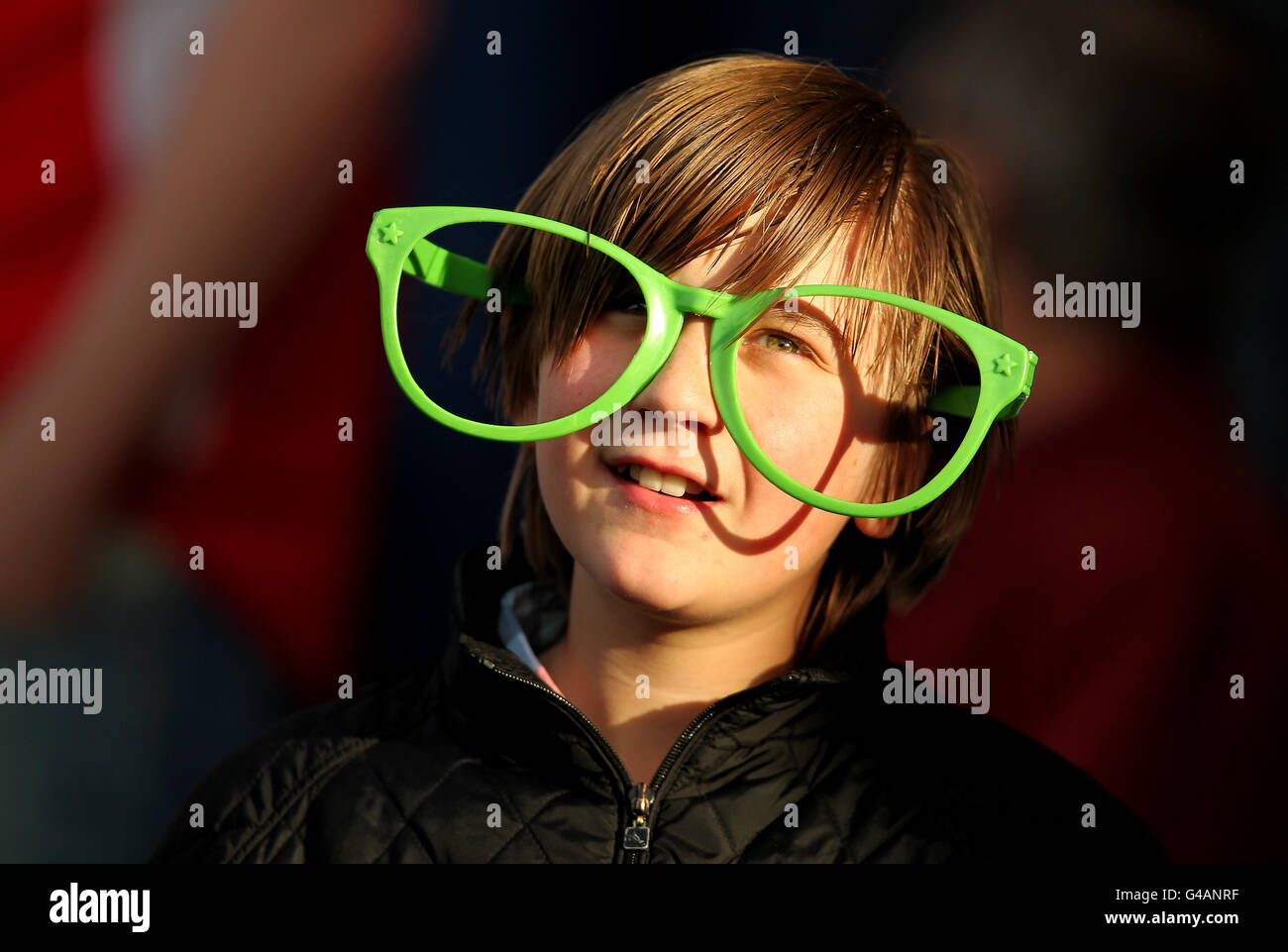 A young Accrington Stanley fan wears large sunglasses in the stands ...