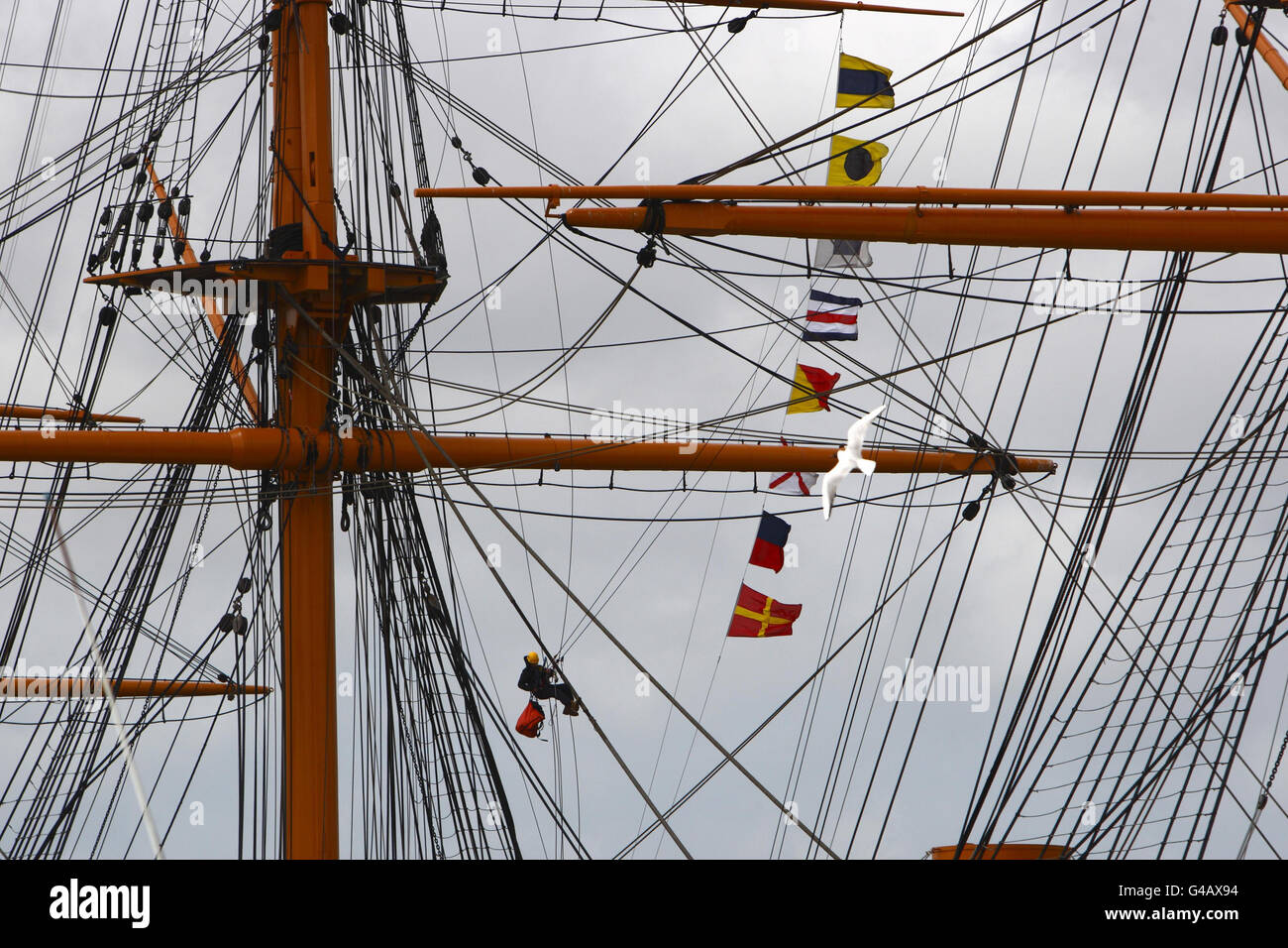 An abseiling engineer braves high winds as he hangs high in the rigging ...