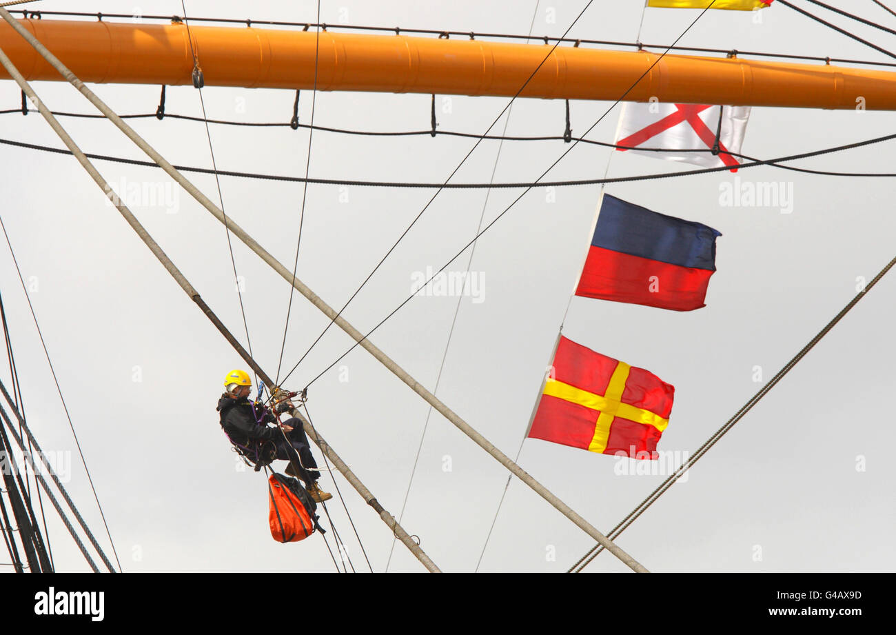 An abseiling engineer in the middle of the rigging of HMS Warrior as he ...