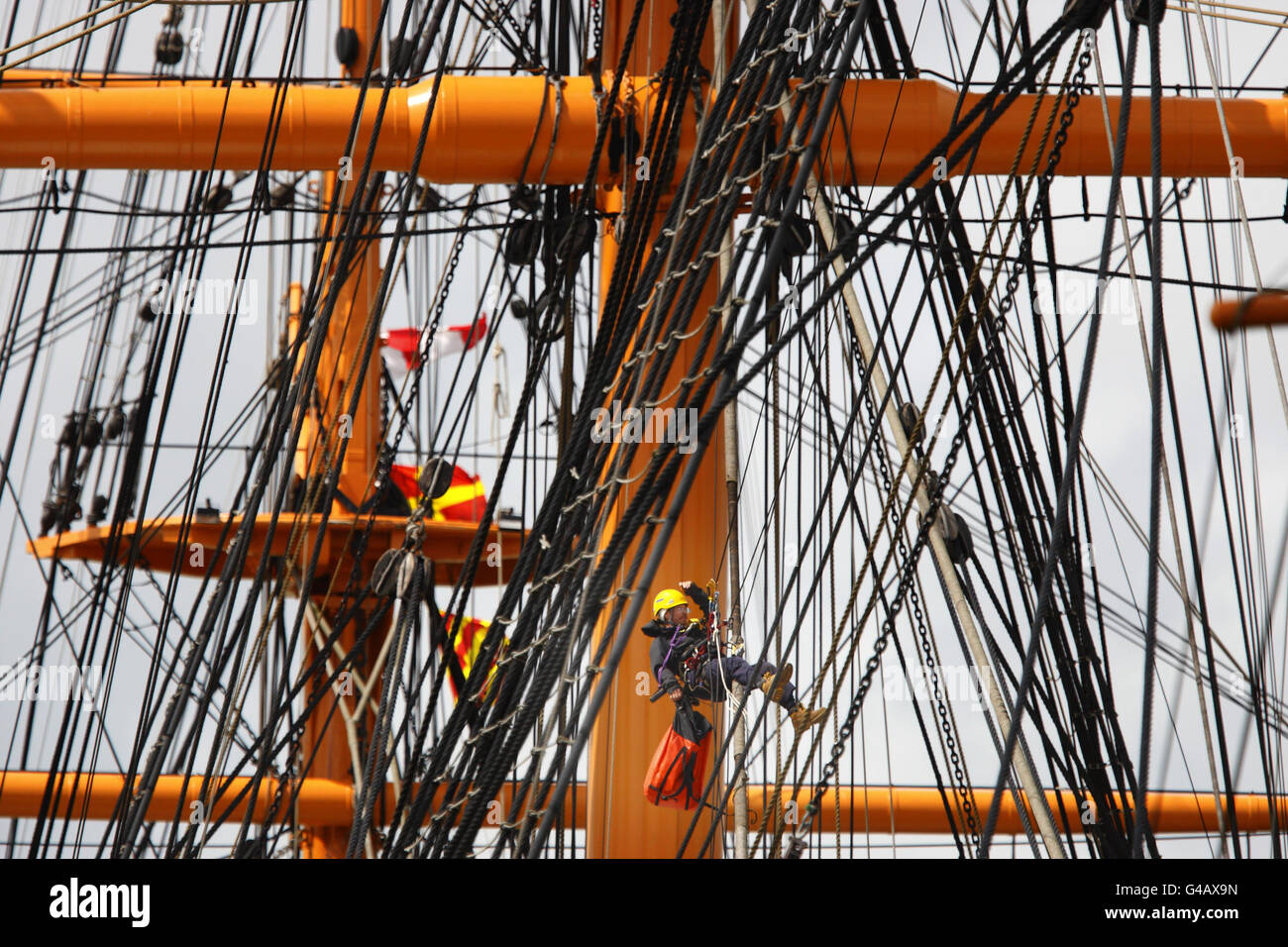 An abseiling engineer in the middle of the rigging of HMS Warrior as he ...