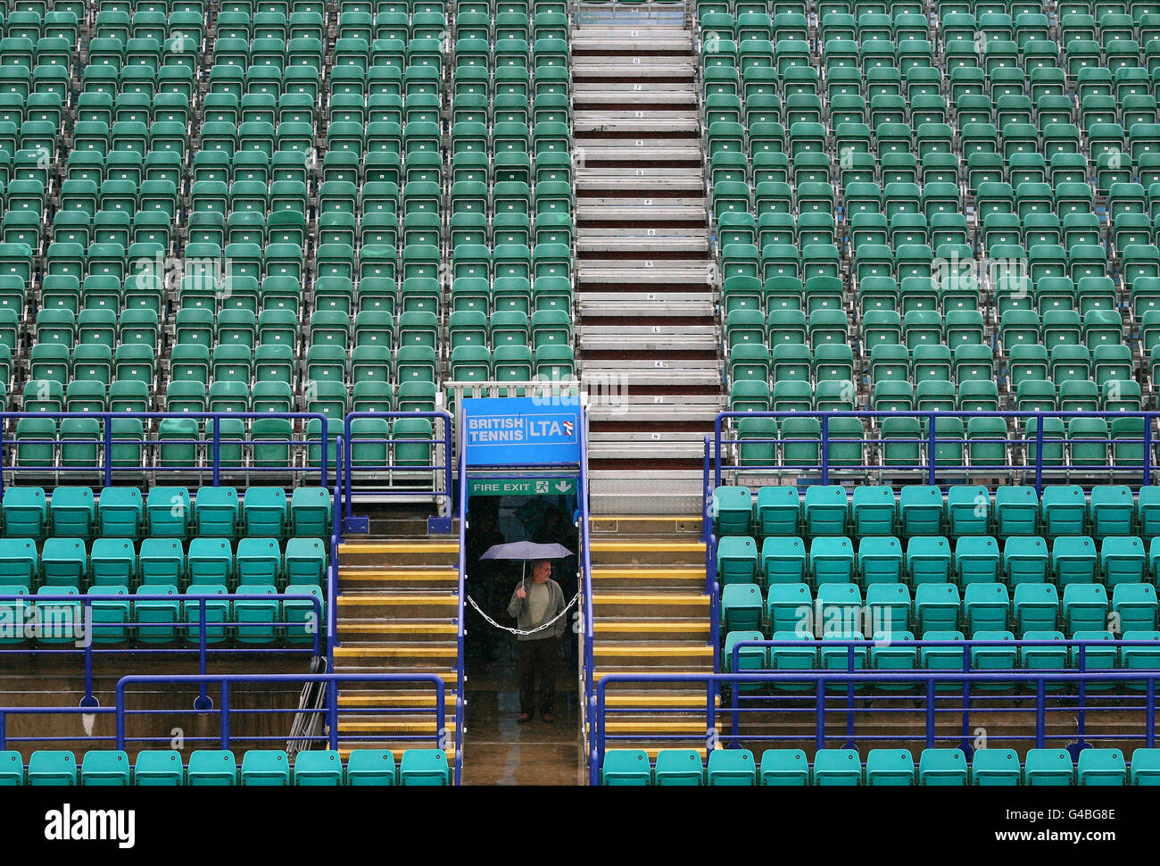 A spectator views Centre Court from under his umbrella as the rain ...
