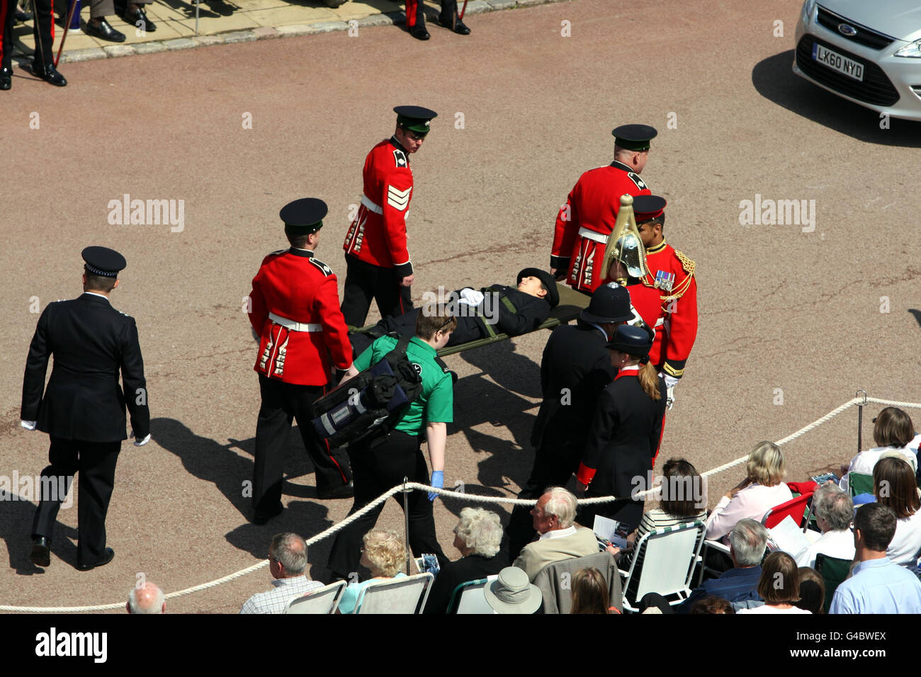 A police officer is carried away on a stretcher after fainting outside ...