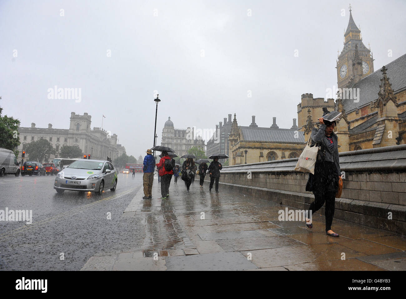 Commuters struggle through the rain outside the Houses of Parliament ...