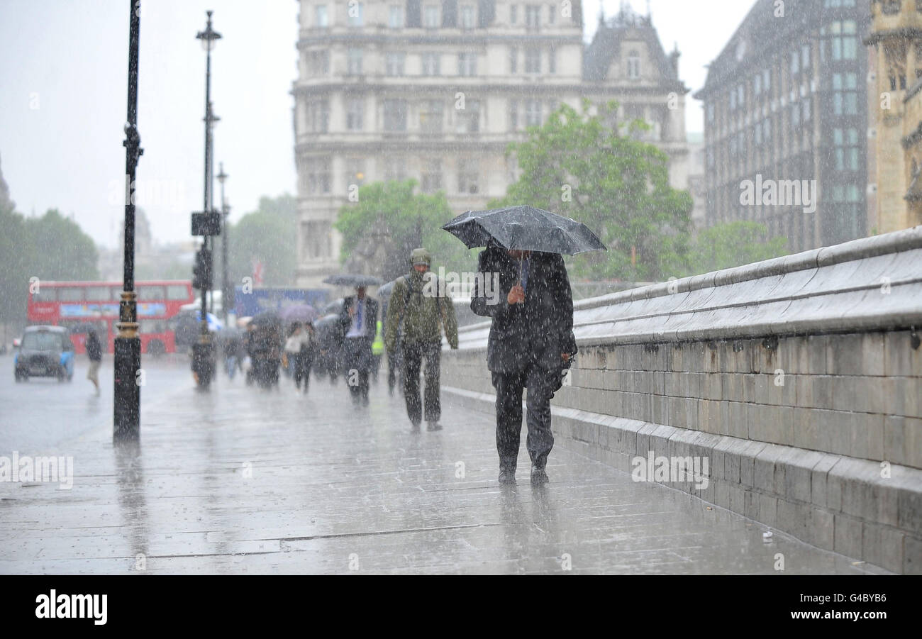 Commuters struggle through the rain outside the Houses of Parliament ...