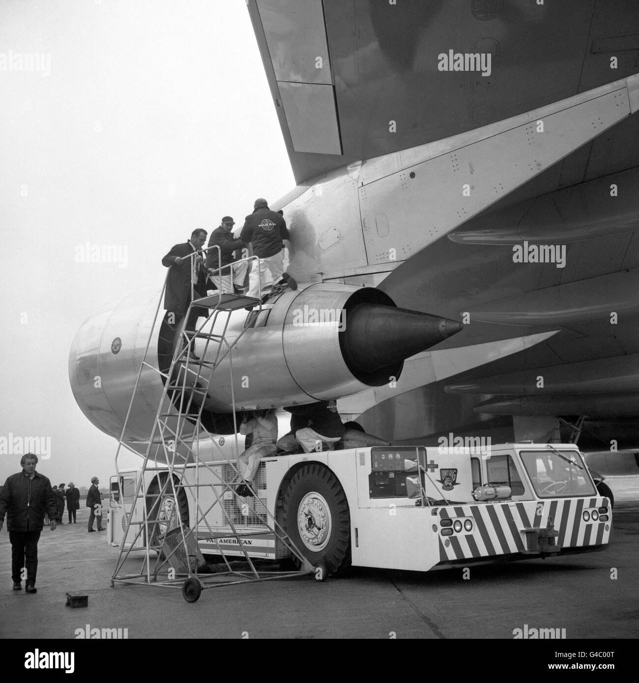 Men are shown working on one of the port engines of the giant Boeing ...
