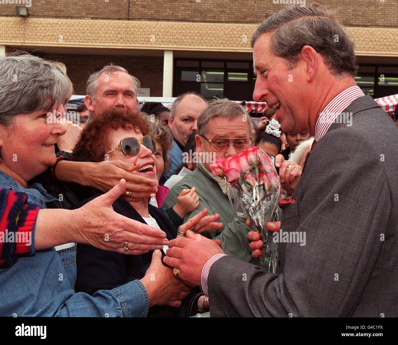 The Prince of Wales smiles as he accepts flowers and handshakes from ...