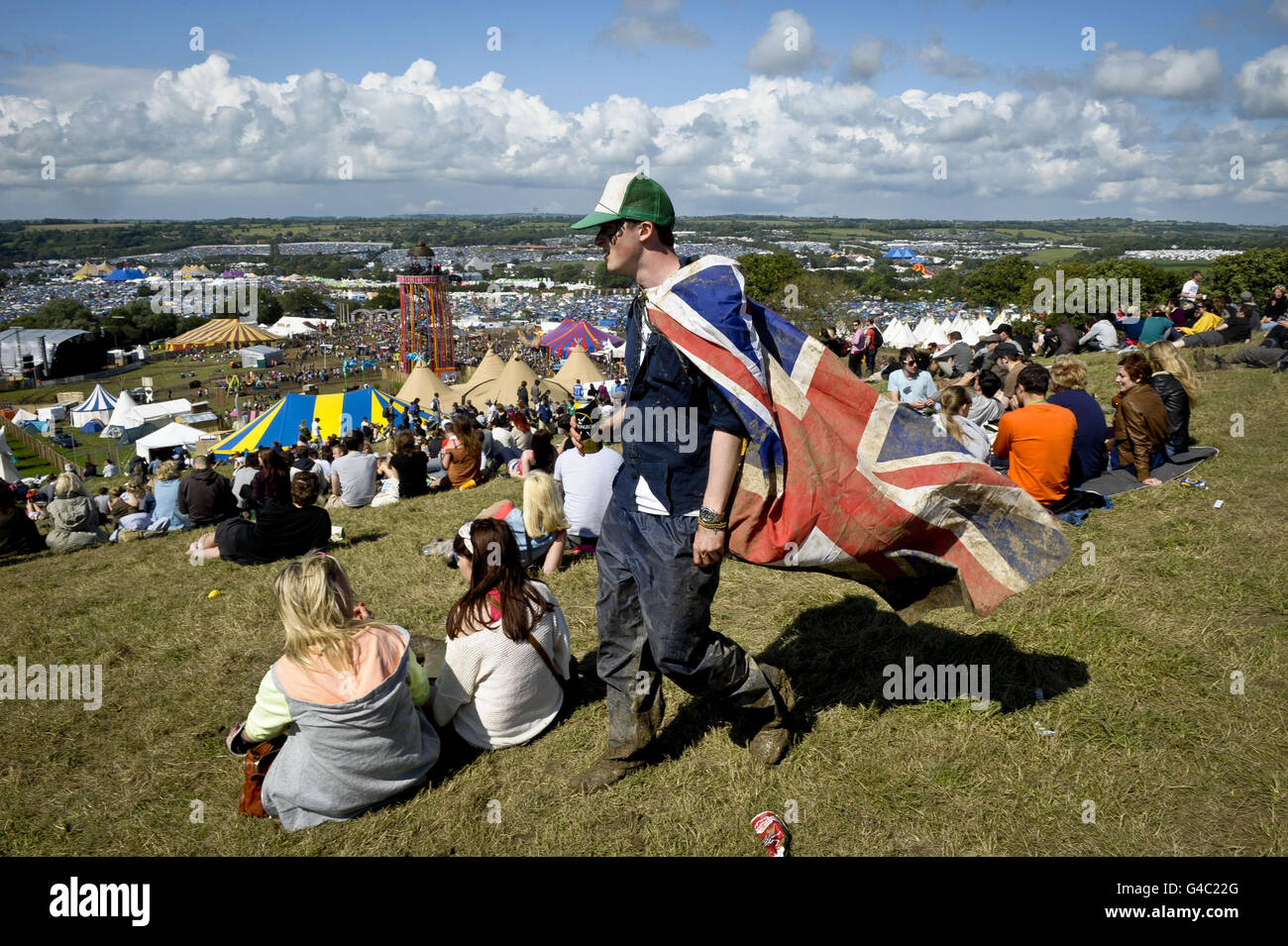 A reveller wears a muddy Union flag as he wanders around in the ...
