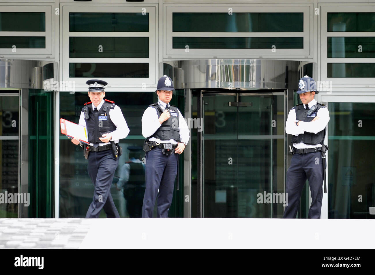 Police officers stand outside the News International offices in Wapping ...