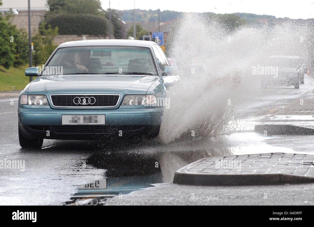 EDS NOTE PIXELATION OF CAR NUMBER PLATE. Cars splash through standing ...