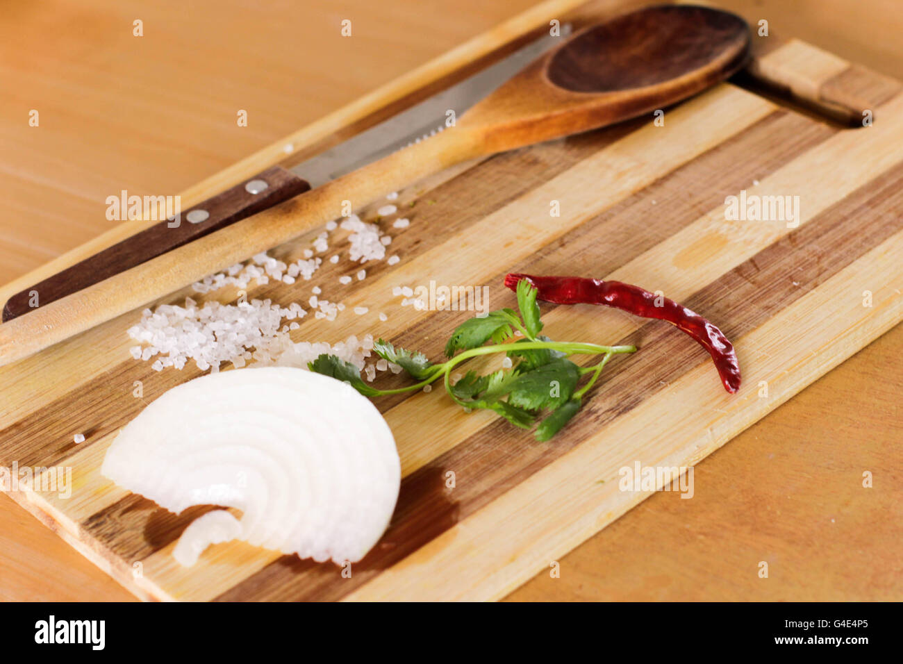 Photograph of a wood table with a knife, spatula, salt, cheese and ...