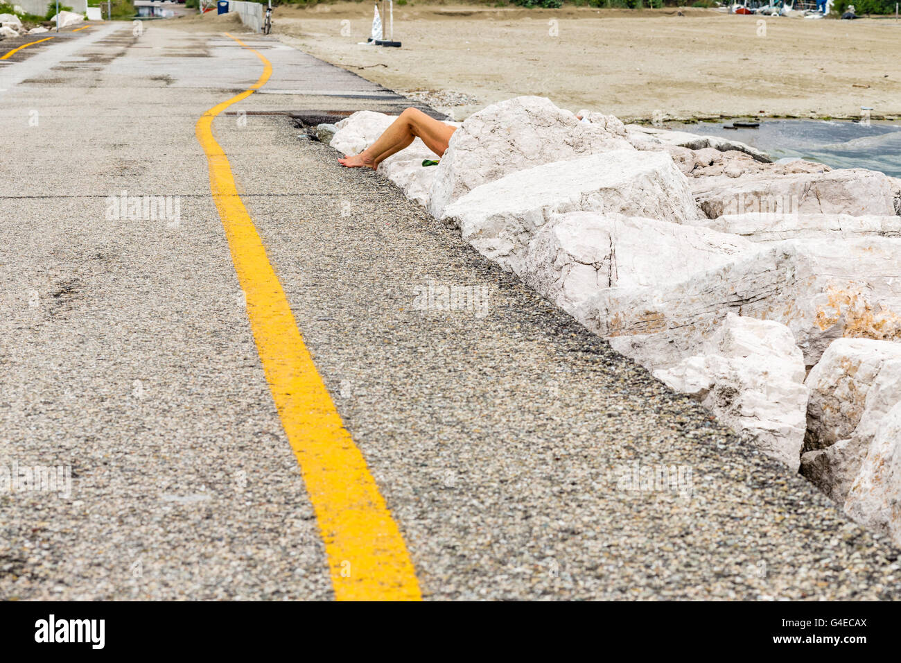 female legs sunbathing on rocks of pier Stock Photo - Alamy