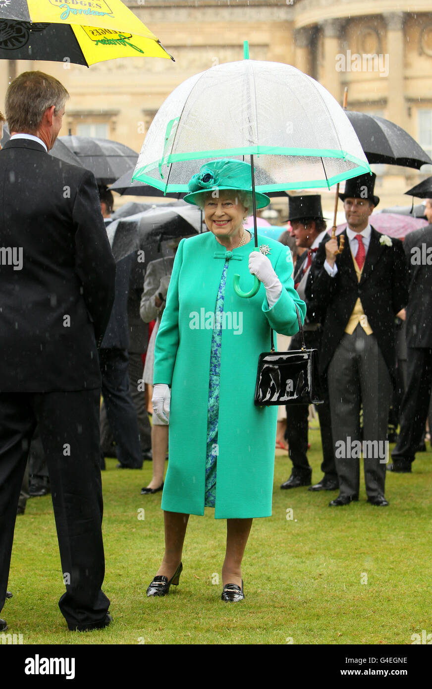 Britain's Queen Elizabeth II shelters from the rain under an umbrella ...