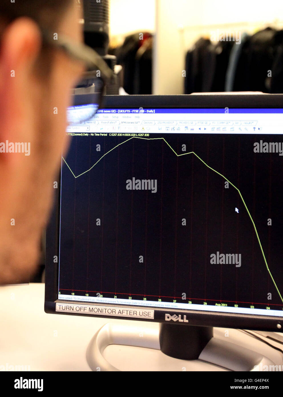 A worker looks at graph showing the FTSE 100 index from mid July to ...