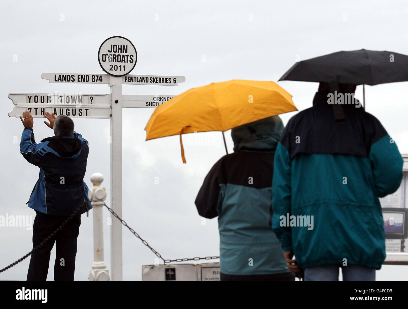 People shelter under umbrellas at John O'Groats in Scotland, as rain ...