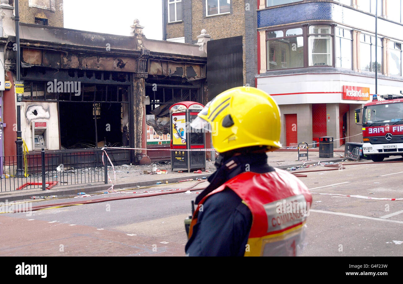 A fire-fighter looks across the street at the burned out shell of a pub ...