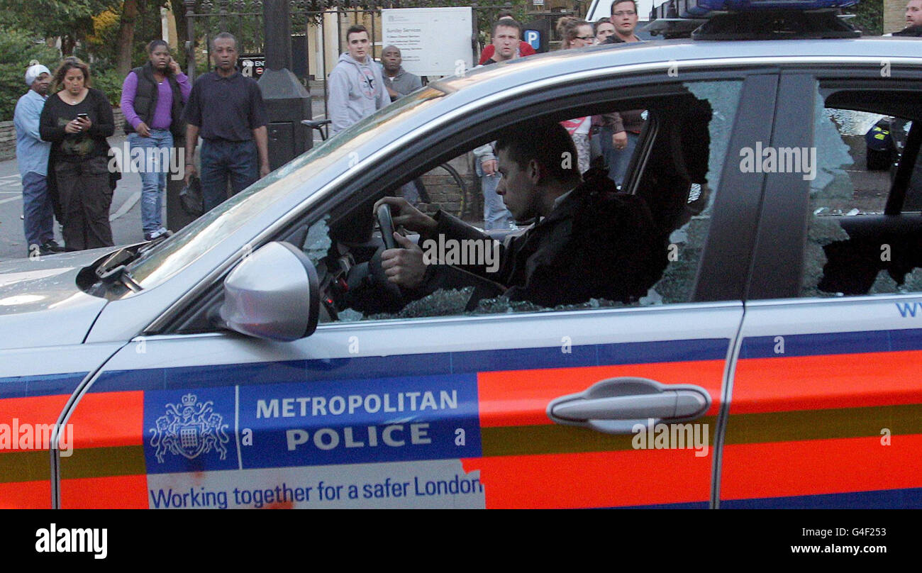 A policeman drives through a crowd after having his windows smashed in ...